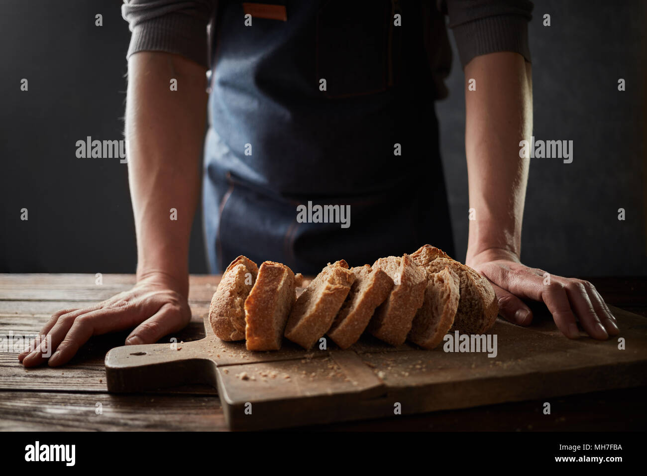 Baker man holding rustic organic loaf of bread in hands rural bakery ...