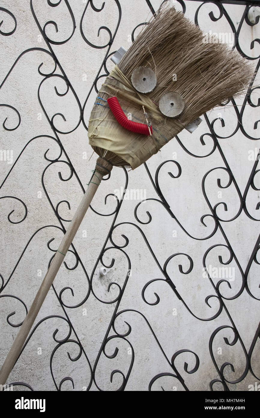 Broom with a smiley face, attached to a wrought-iron gate in Taurinya ...
