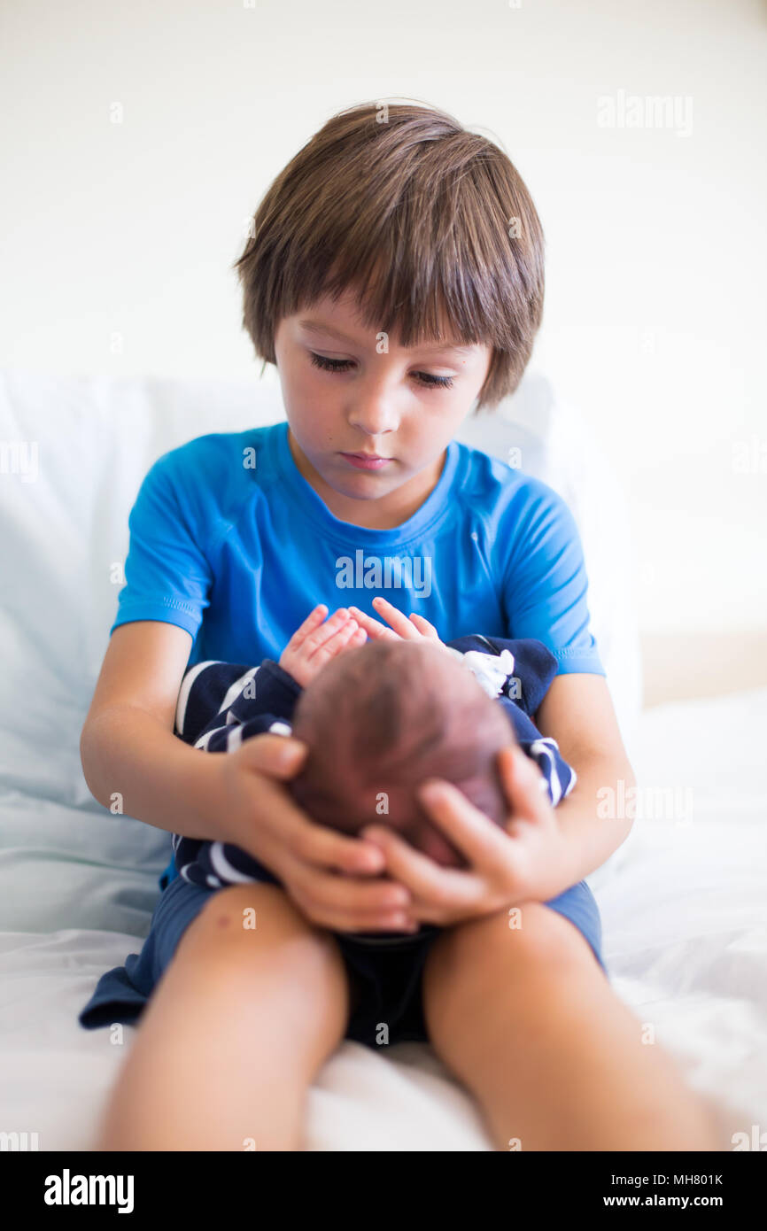Cute boy, brother, meeting for the first time his new baby brother at ...