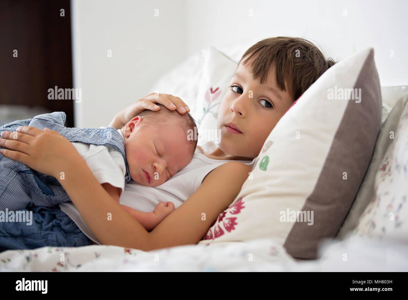 Beautiful boy, hugging with tenderness and care his newborn baby ...