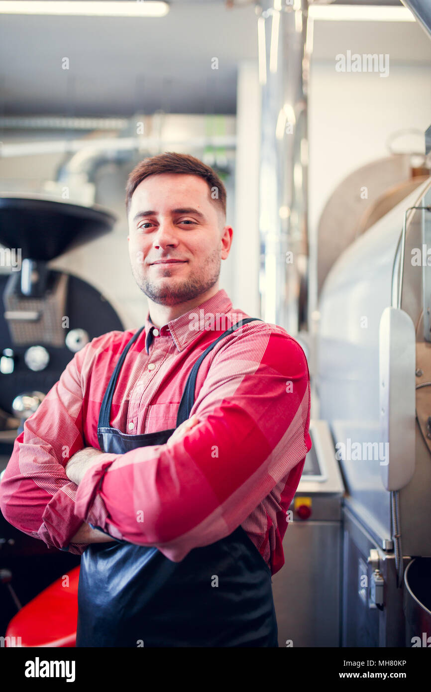 Image of young brunet in apron on background of industrial coffee ...
