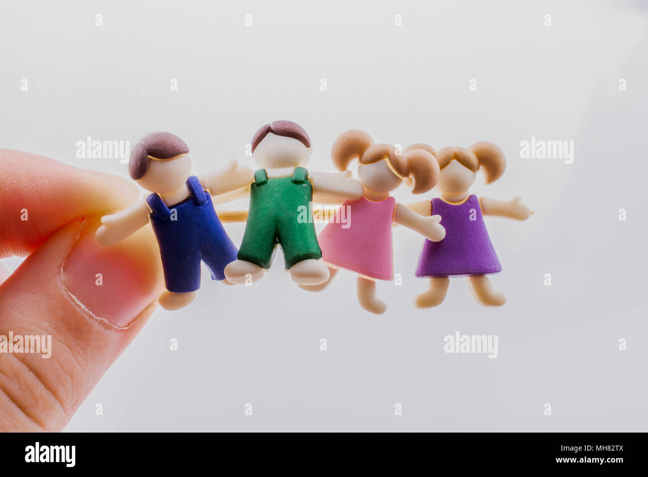 Little colorful boys and girls kid figurines in hand Stock Photo - Alamy