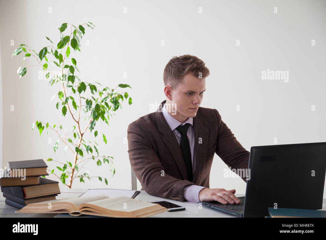 a man in a business suit works at the computer with books in the Office ...