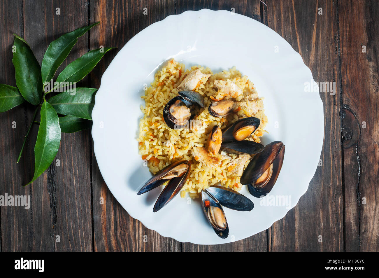 Rice with meat, vegetables and mussels on an old table close-up. Top ...