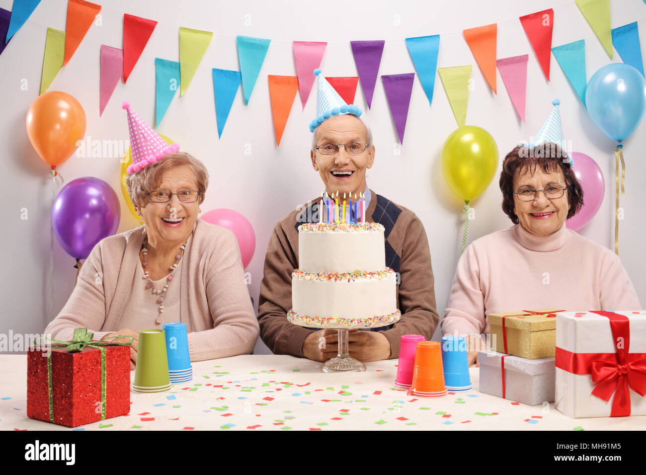 Seniors with party hats and a cake celebrating a birthday Stock Photo ...