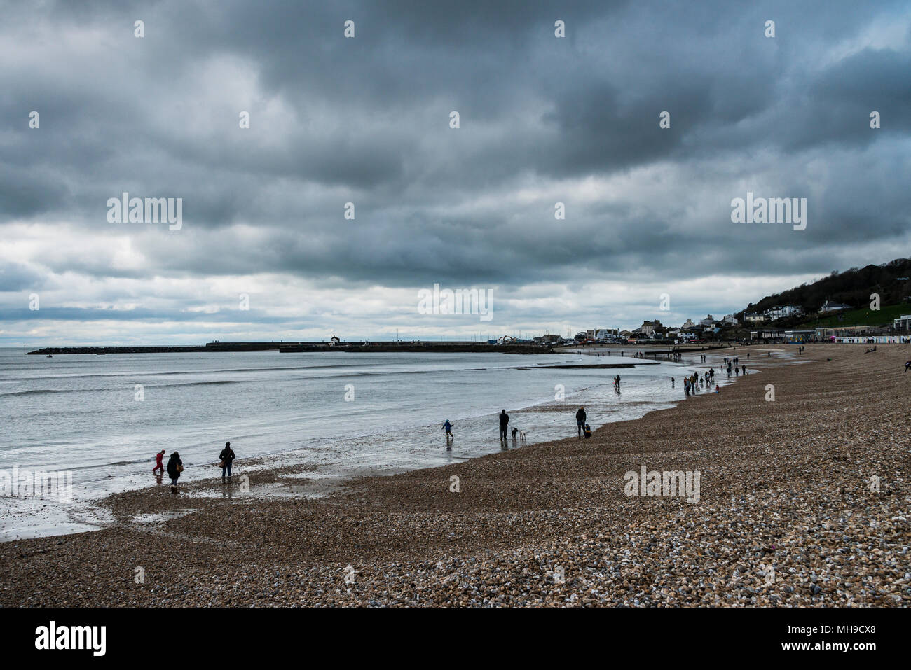 A view of the Cobb in Lyme Regis with people on the shingle beach Stock ...
