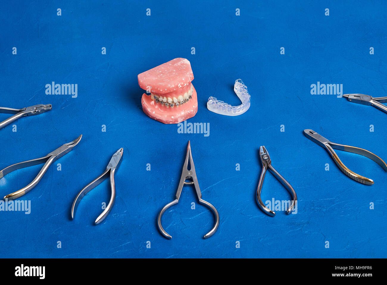 Orthodontic model and set of medical metal orthodontic tools on blue ...