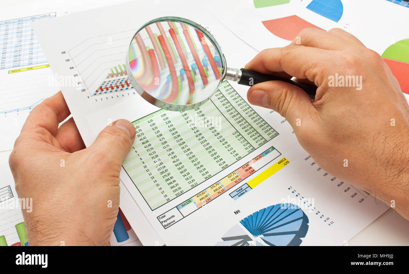 magnifying glass in hand and working paper chart Stock Photo - Alamy