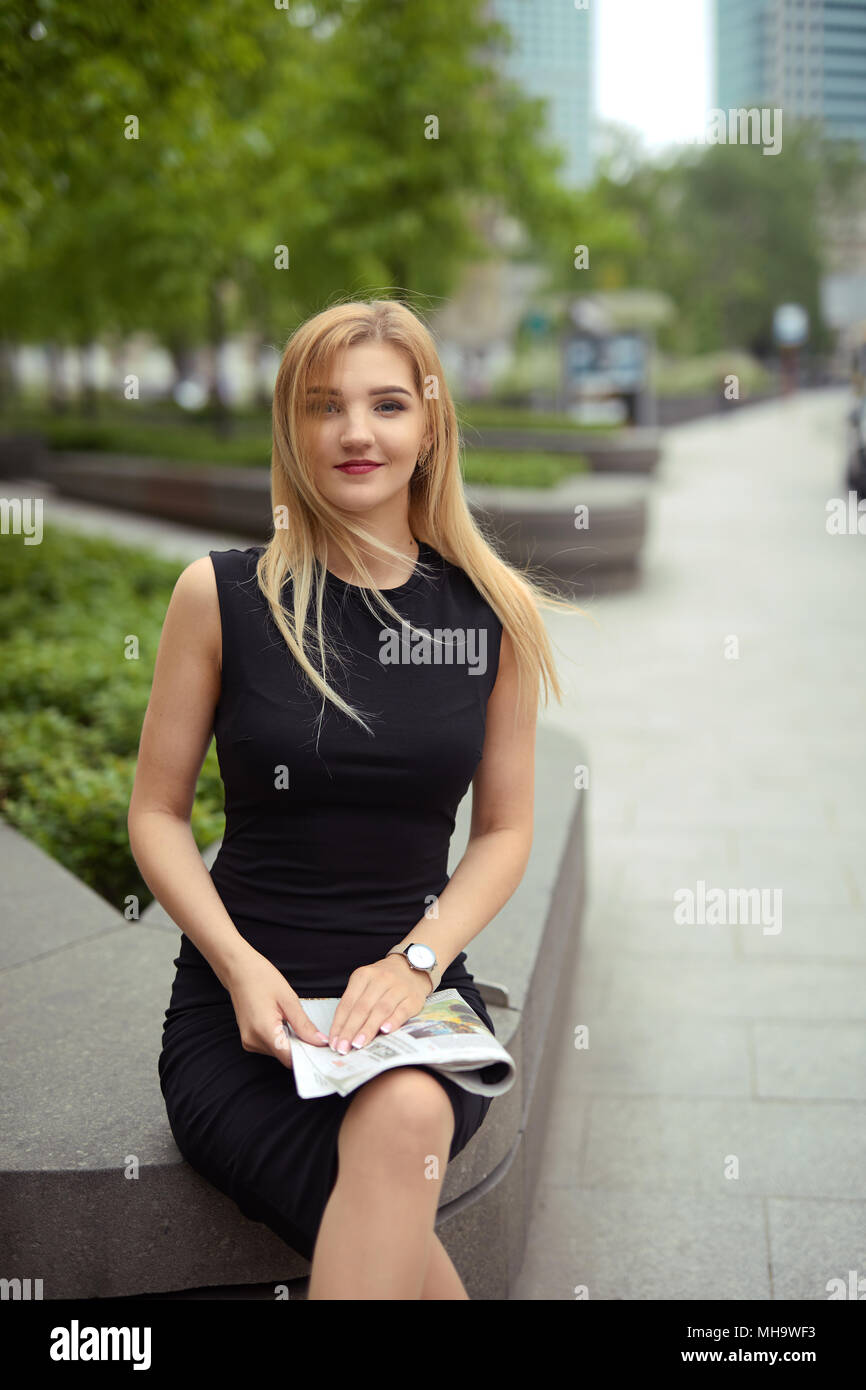 Smart blonde girl sitting with newspaper and read Stock Photo - Alamy