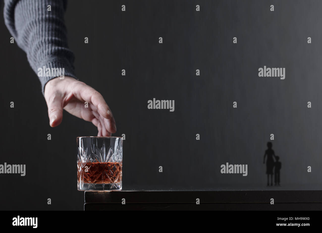 Man's hand reaches for a glass of alcohol. Conceptual image on the ...