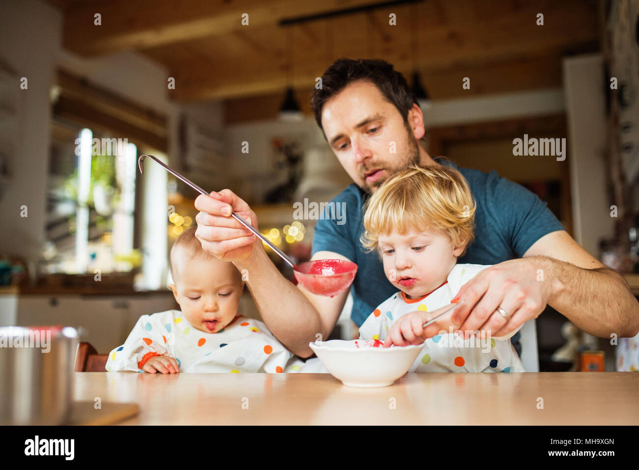 Father feeding two toddlers at home Stock Photo - Alamy
