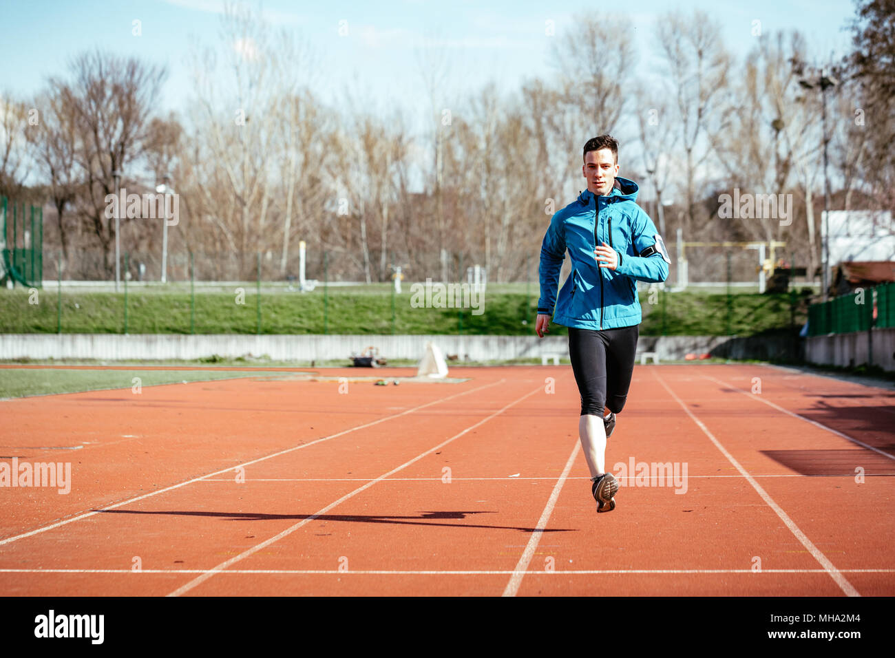 Athletic fit young sport man in full body length on tartan track on the ...