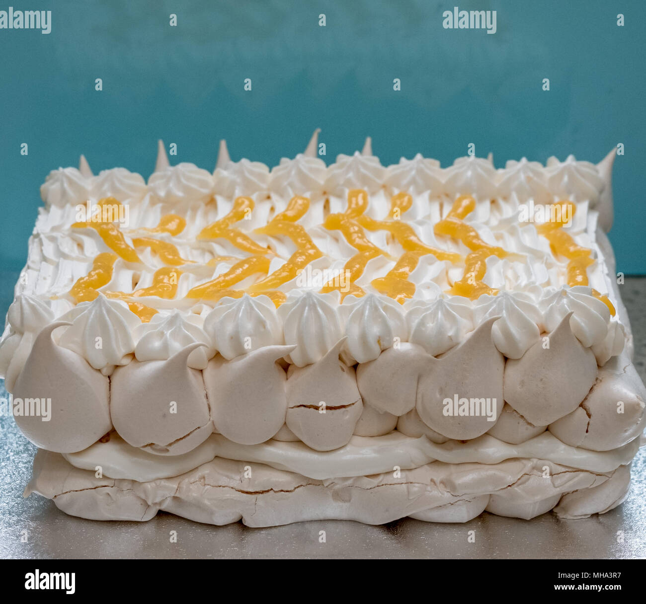 Piped meringue pavlova cake decorated with cream and lemon curd in a ...