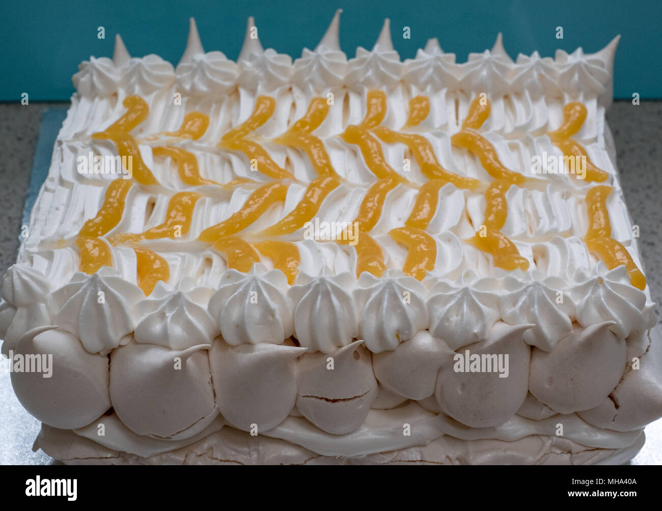 Piped meringue pavlova cake decorated with cream and lemon curd in a ...