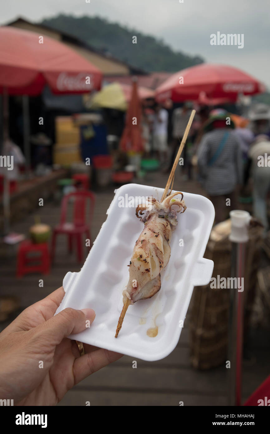 A tourist woman holds an octopus skewer at the renowned Crab Market in ...