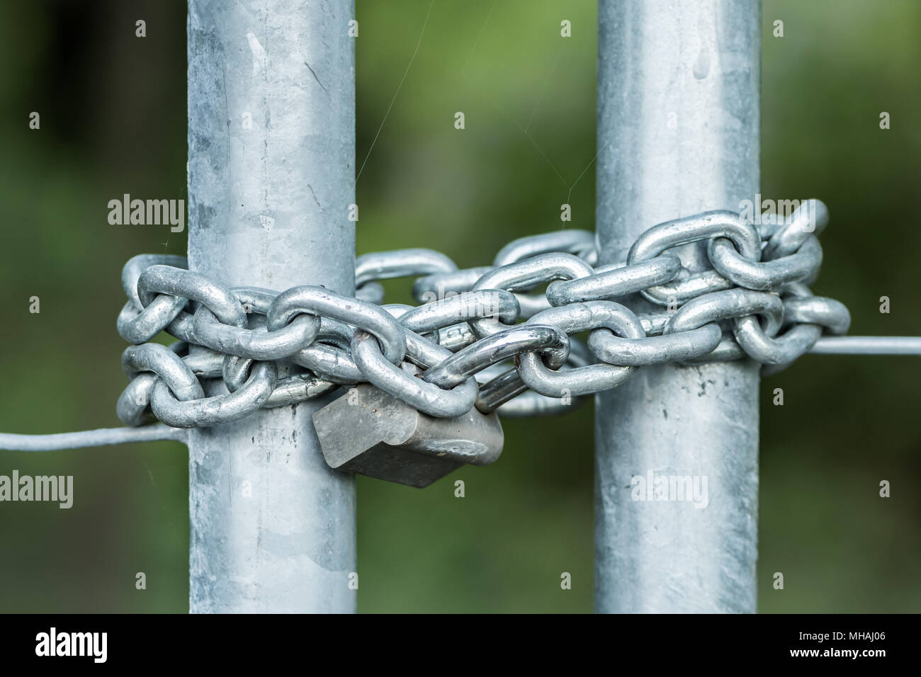 Strong silver iron chain and padlock, green background Stock Photo - Alamy