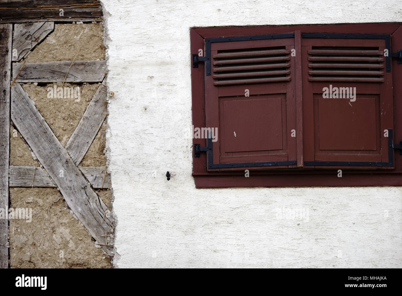 A striking wooden window hatch in a barn wall with a peeling plaster ...