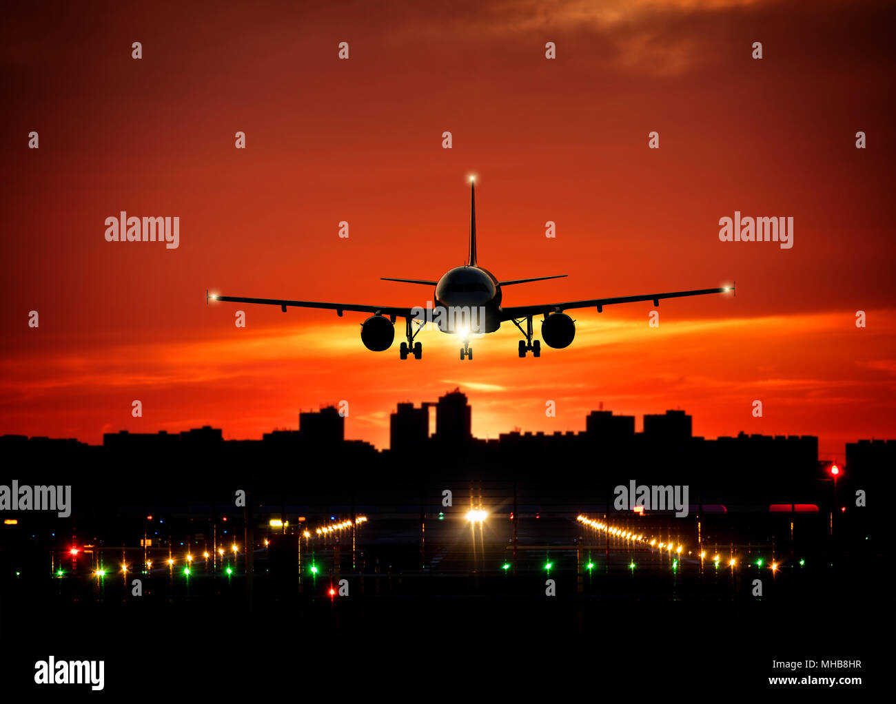 Passengers commercial airplane landing on runway with dramatic sunset ...