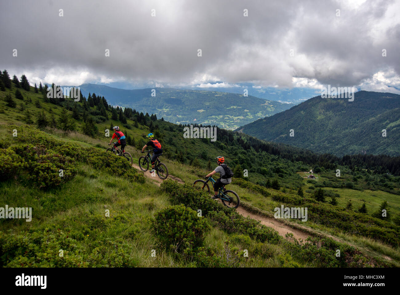 A group of men on mountain bikes ride a trail along a ridge near the ...