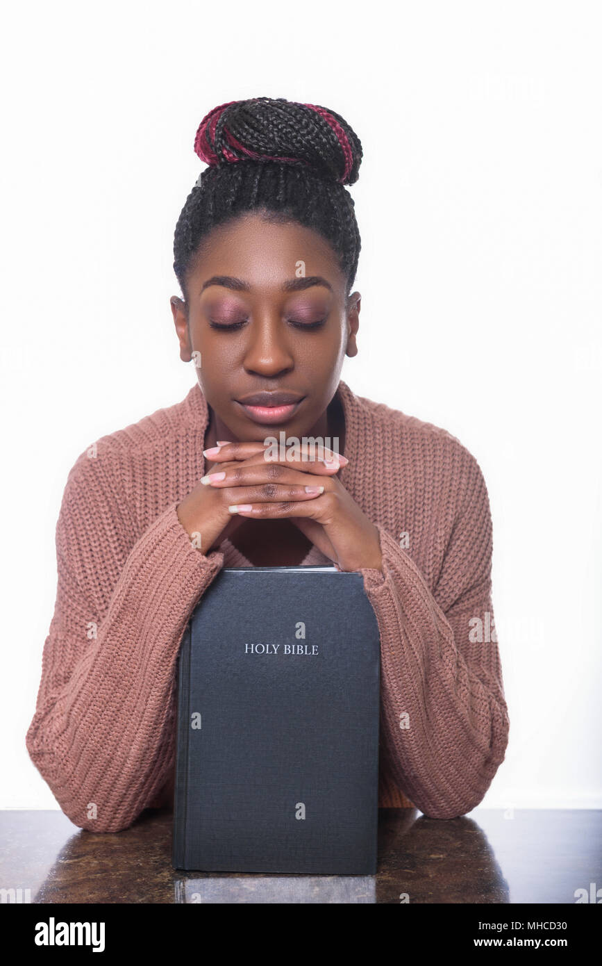 A young African American woman praying over the Holy Bible Stock Photo ...