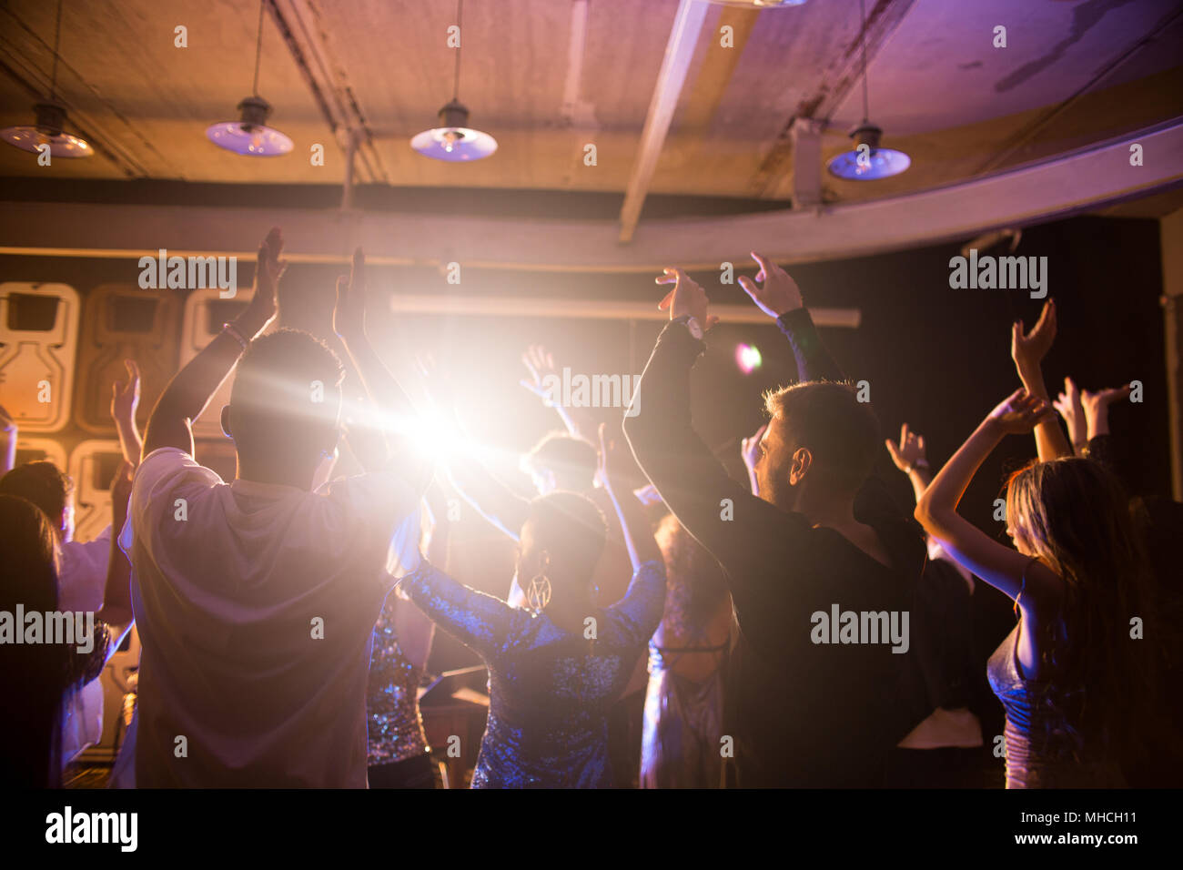 Back view at crowd of trendy young people dancing in nightclub and ...