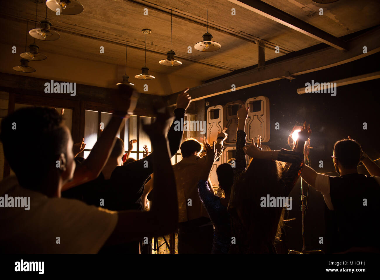 Backlit crowd of trendy young people having fun in raving nightclub ...