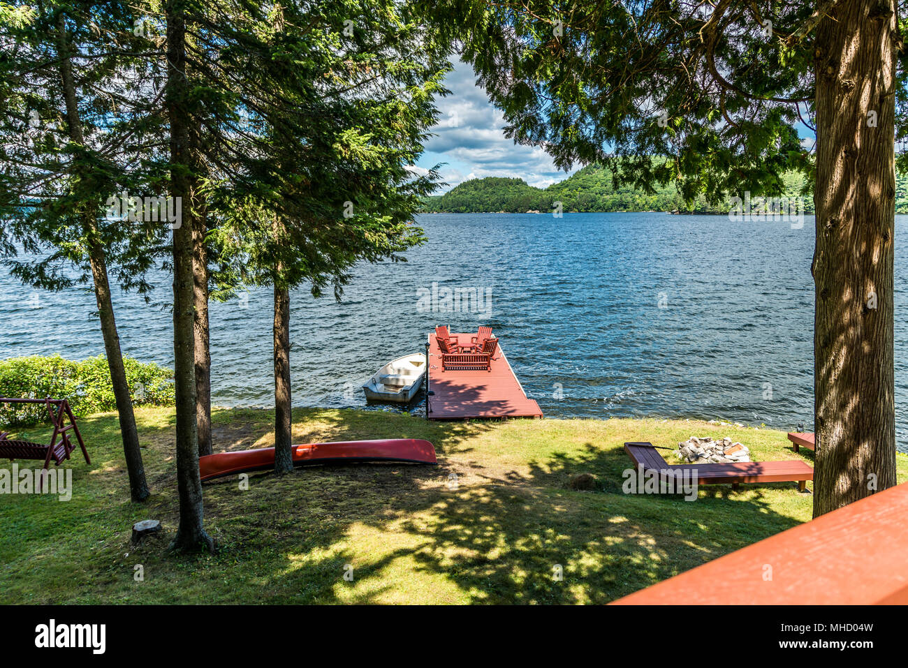 Lake side property with canoe, boat, wooden swing and chairs in a ...