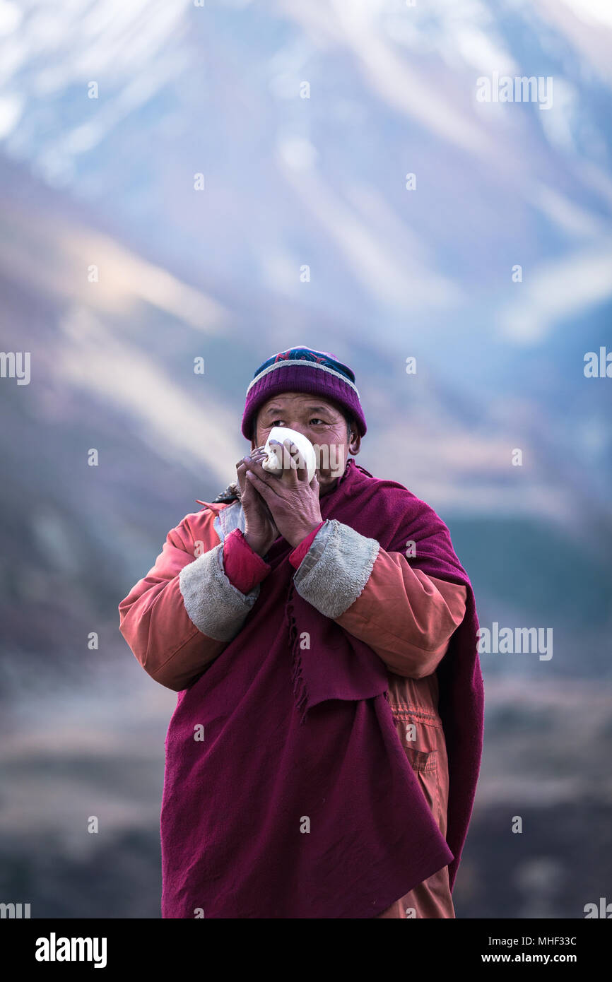 A monk blows into a conch shell at a monastery on the border of Nepal ...