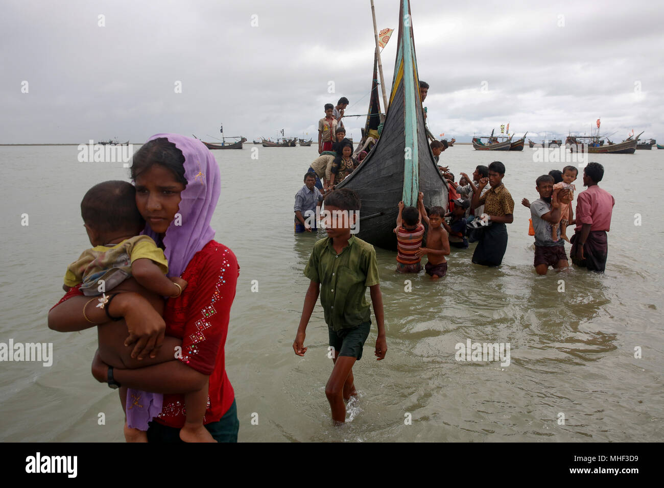 Rohingya refugees walk to the shore after crossing the Bangladesh ...