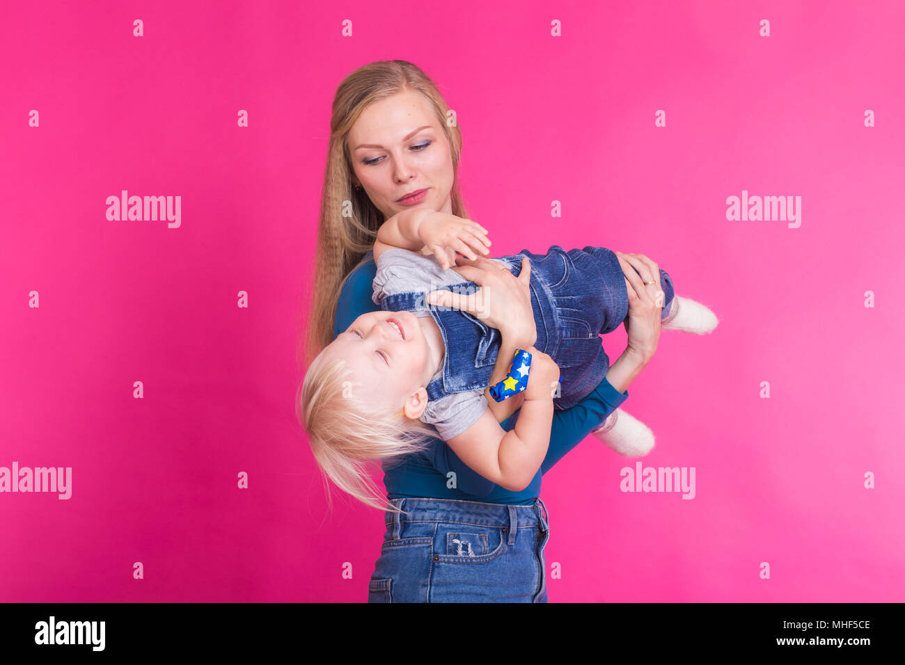 happy little girl and her mother having fun over pink background Stock ...