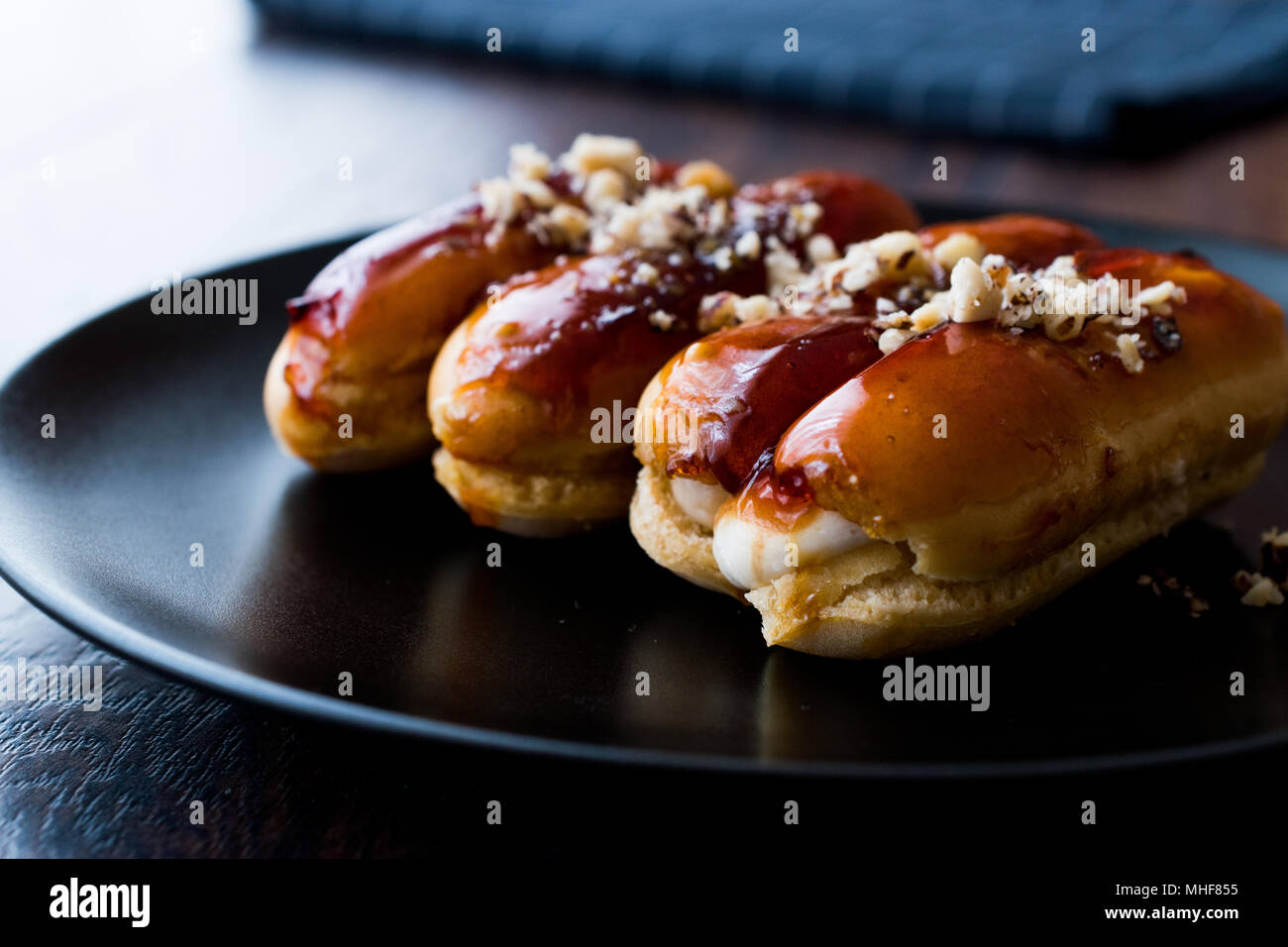 Caramel Eclairs with Hazelnut and cream in black plate. Dessert Concept ...