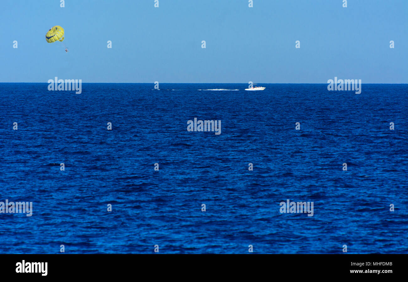 Parachute over the sea against a blue sky and clear sea water, towing ...