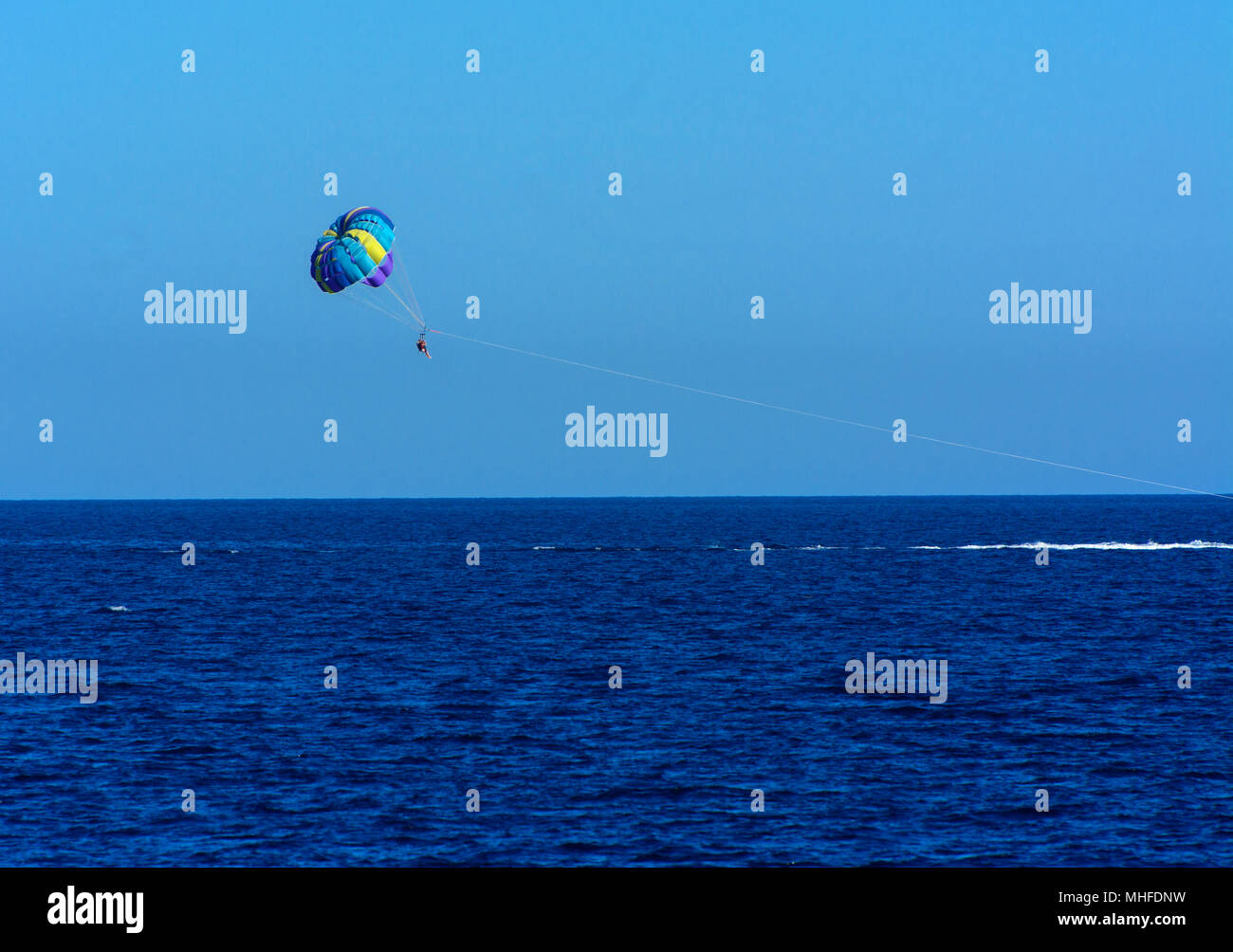 Parachute over the sea against a blue sky and clear sea water, towing ...