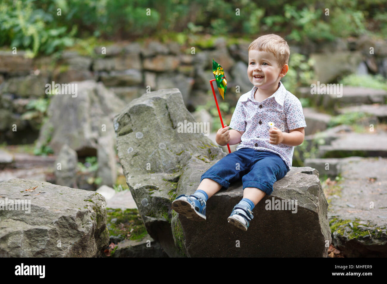 Little boy playing in park with windmill pinwheel. Outdoors leisure ...