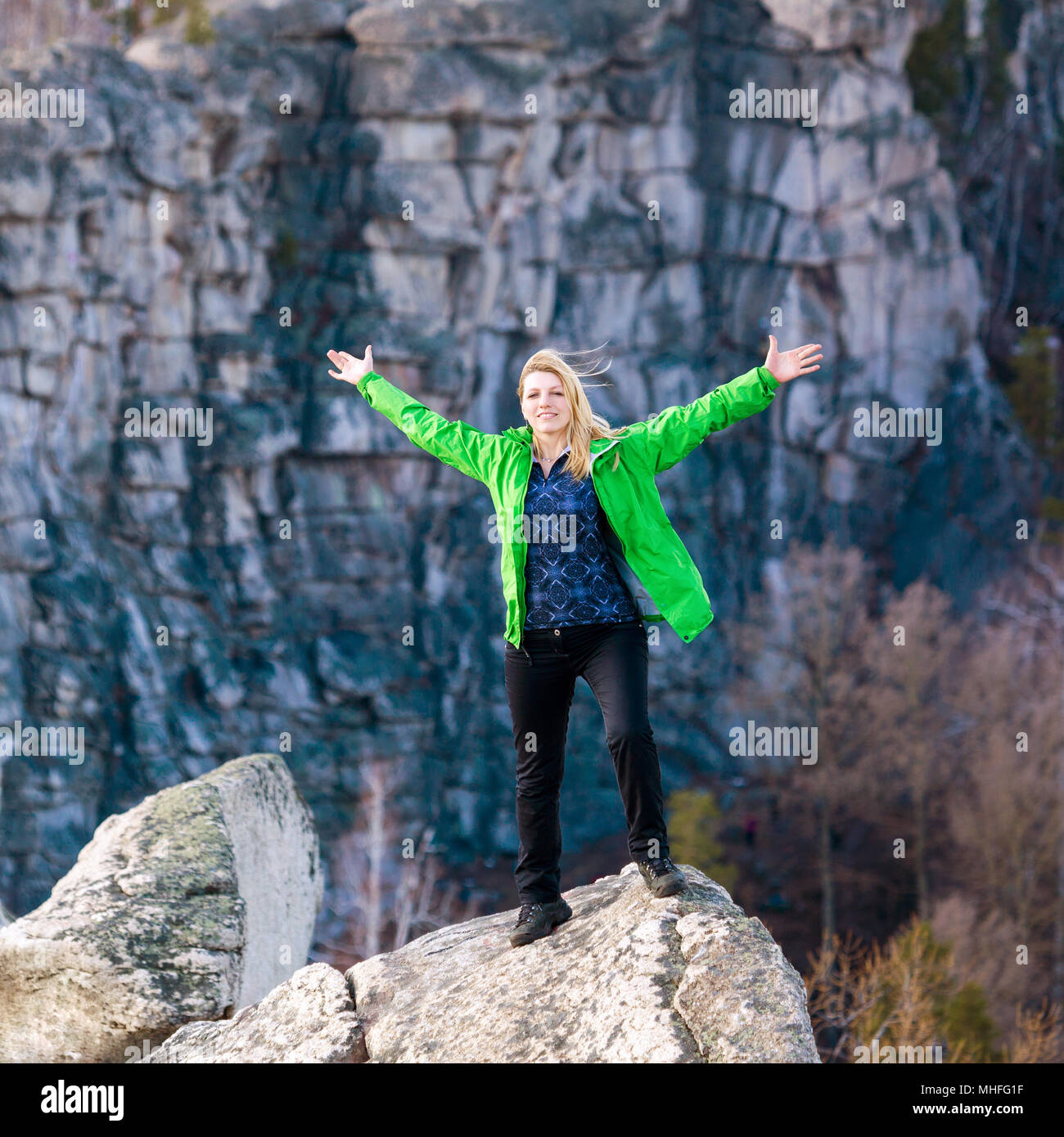 Young woman standing on cliff edge with raised hands Stock Photo - Alamy