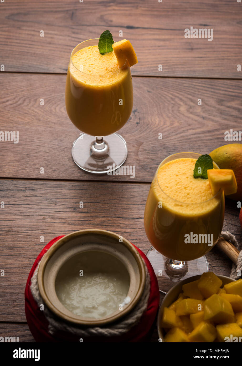 Mango Lassi or smoothie in big glass or small bottles with curd, cut ...