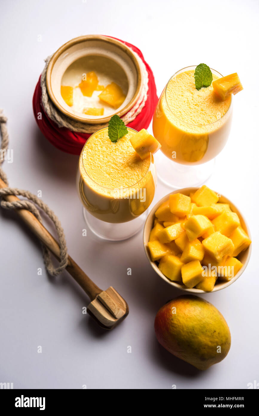 Mango Lassi or smoothie in big glass or small bottles with curd, cut ...