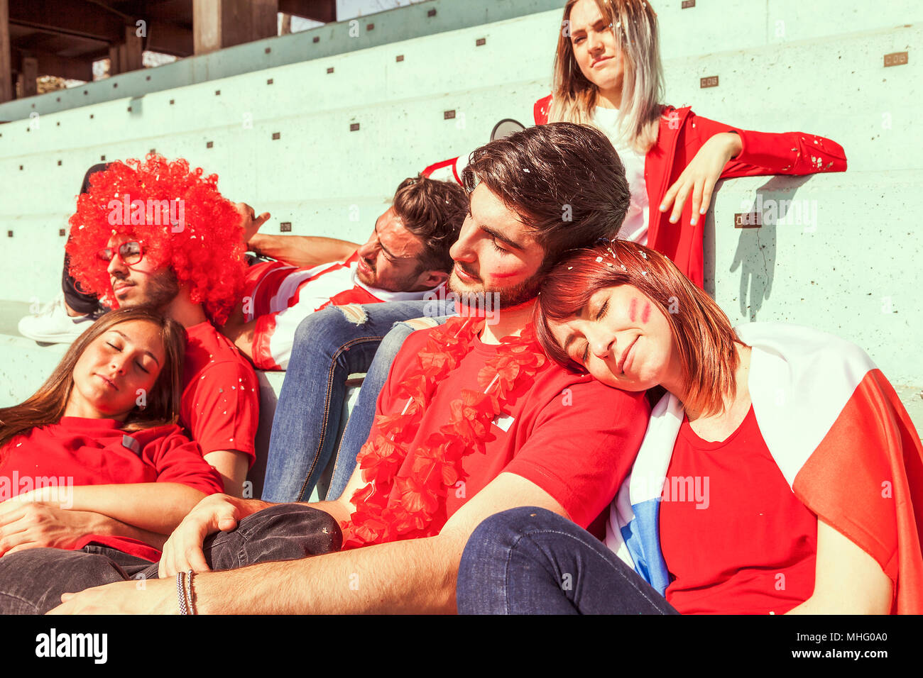 young group of supporter fans dressed in red color relaxing lying down ...