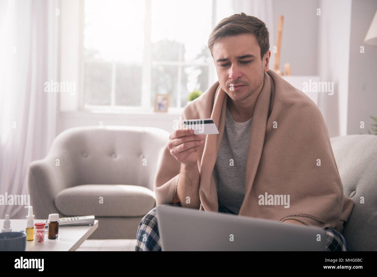 Sad ill man looking at the laptop screen Stock Photo - Alamy