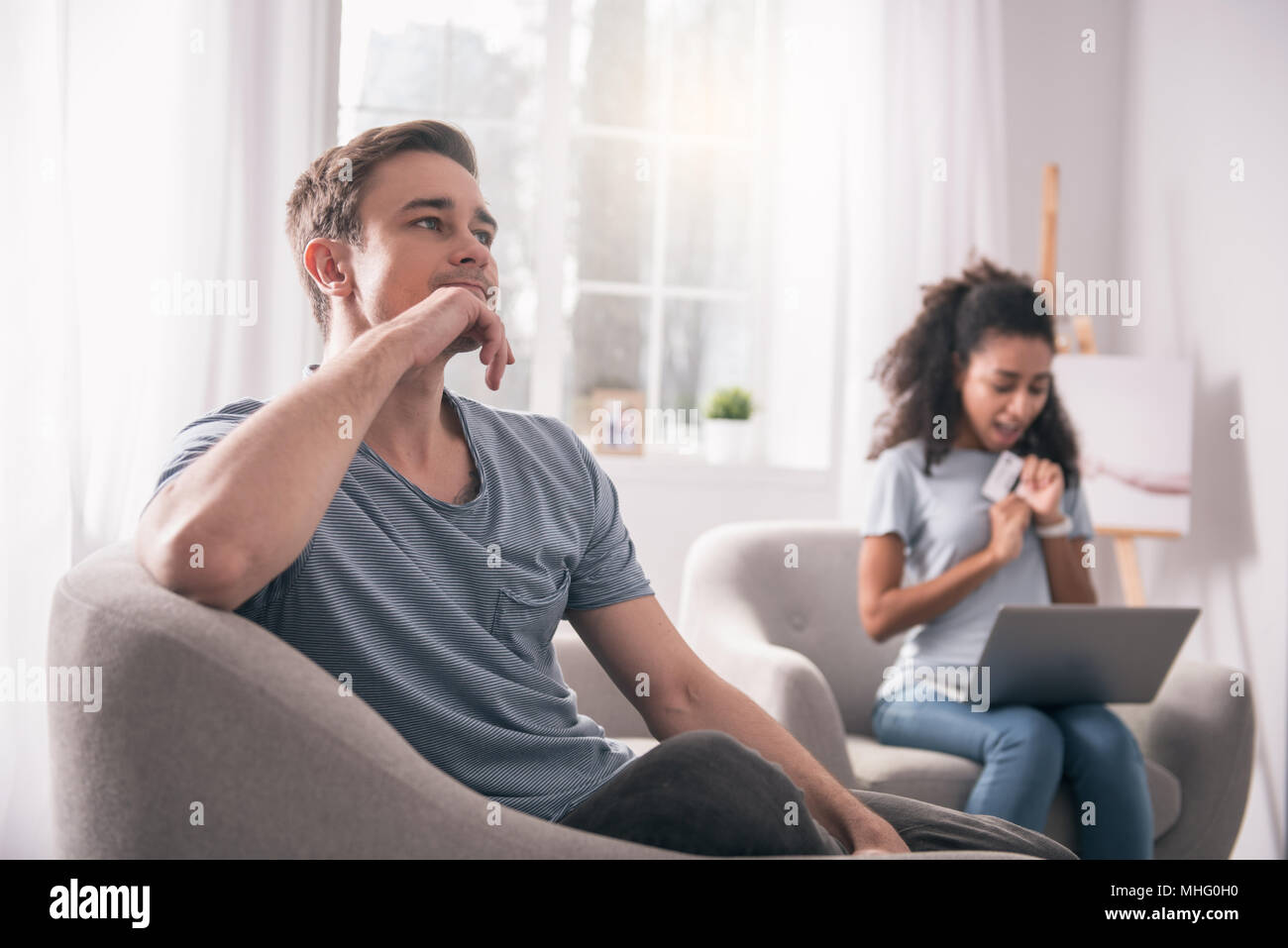 Nice thoughtful man sitting on the sofa Stock Photo - Alamy