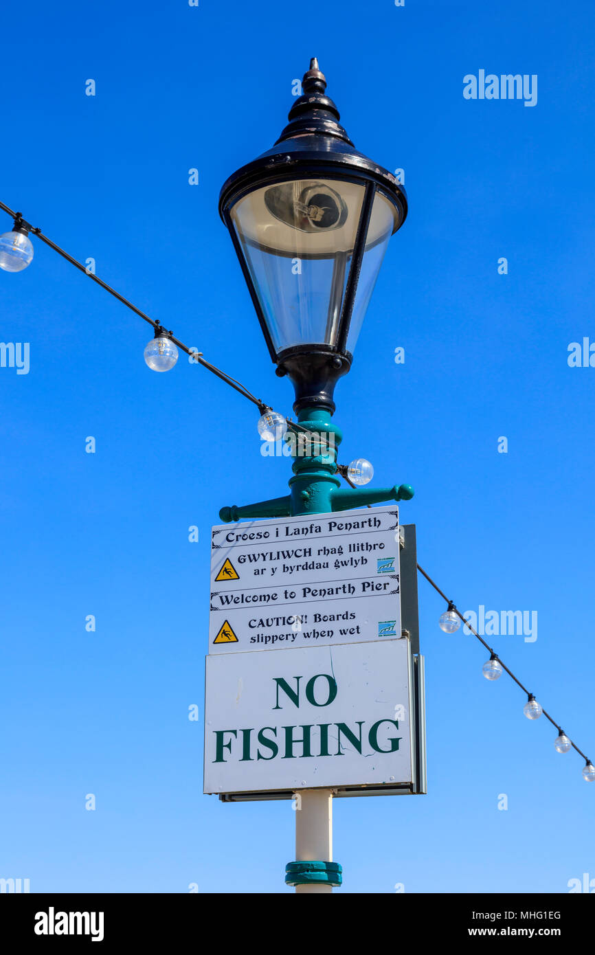 No Fishing sign on a lampost on Penarth Pier, also bi-lingual signs in ...
