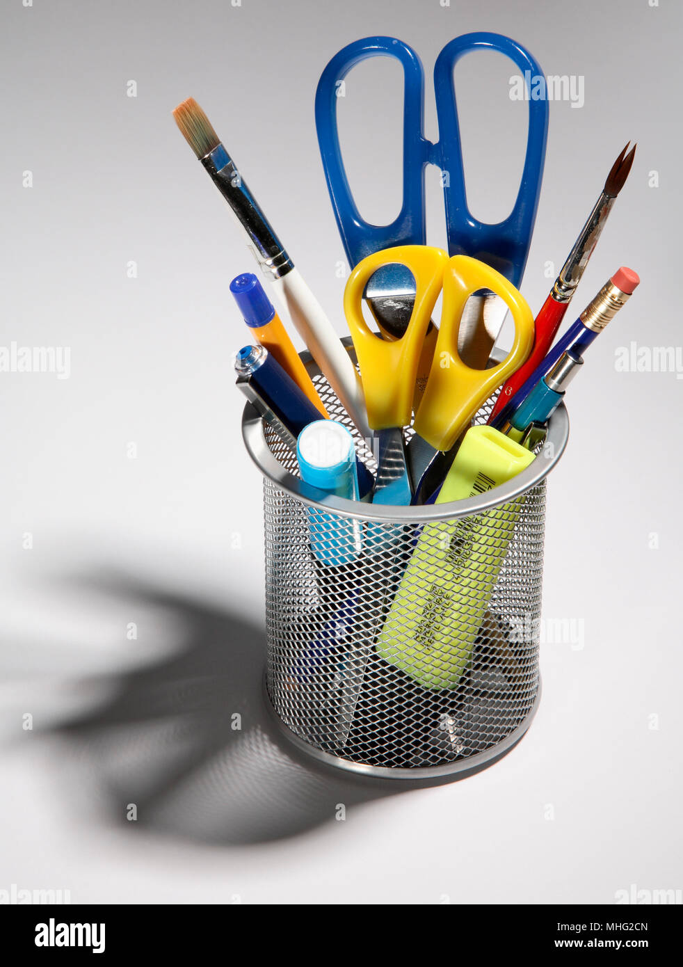 Pens, pencils, scissors and brushes in a pot, on a white background ...