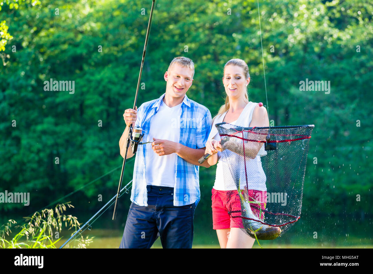 Couple sport fishing bragging with fish caught Stock Photo - Alamy