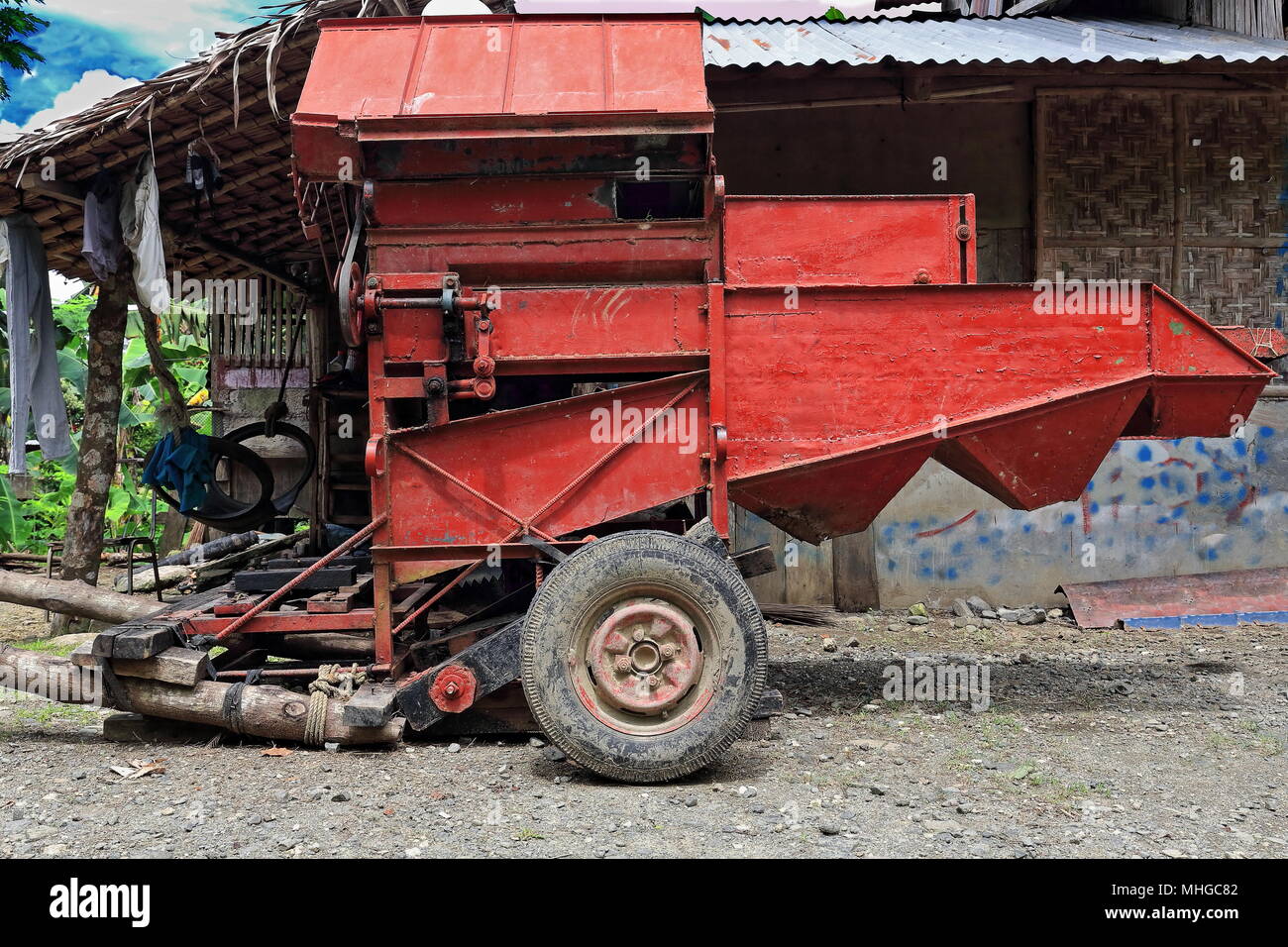 Old red combine harvester for rice cropping on the outside of a ...