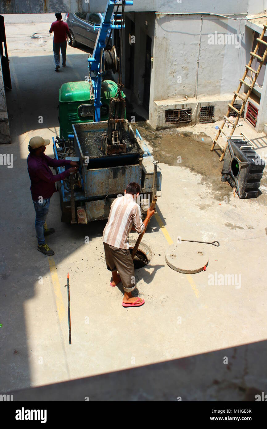 Man cleaning a blocked manhole with the help of a manhole cleaning ...
