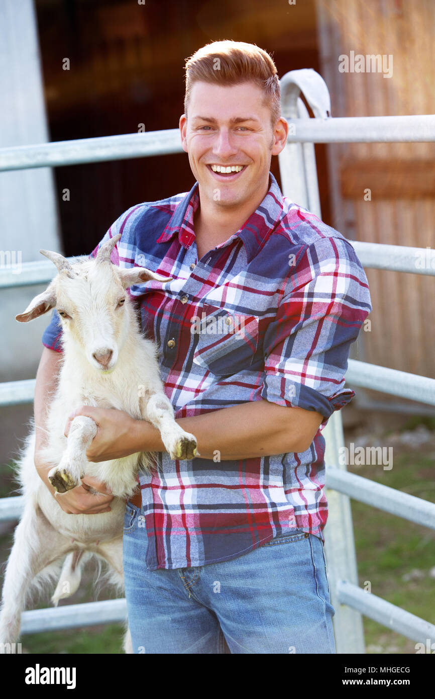 portrait of handsome man at a farm holding a goat Stock Photo - Alamy