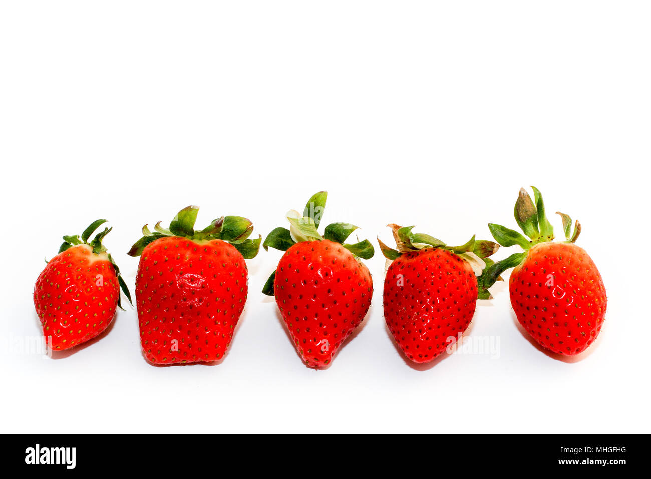 Five fresh and natural red strawberries of different shapes with green ...