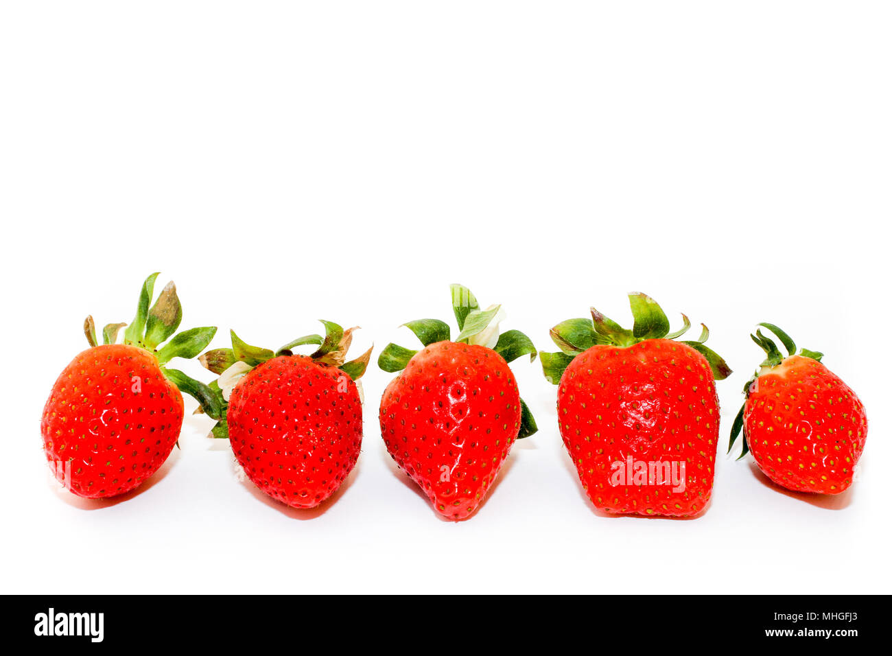 Five fresh and natural red strawberries of different shapes with green ...