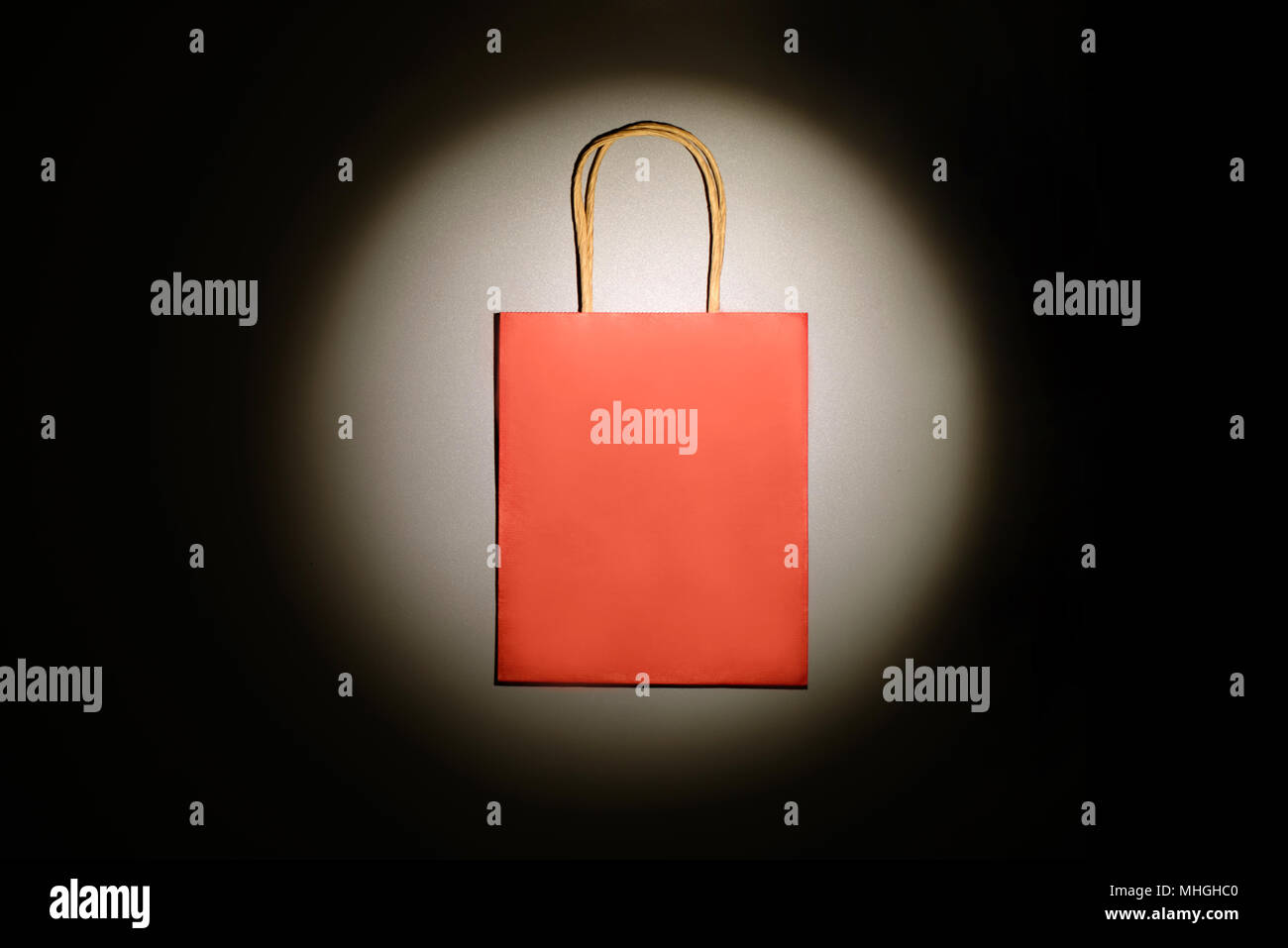 Red shopping bag in the ray of scenic spot light over dark background ...