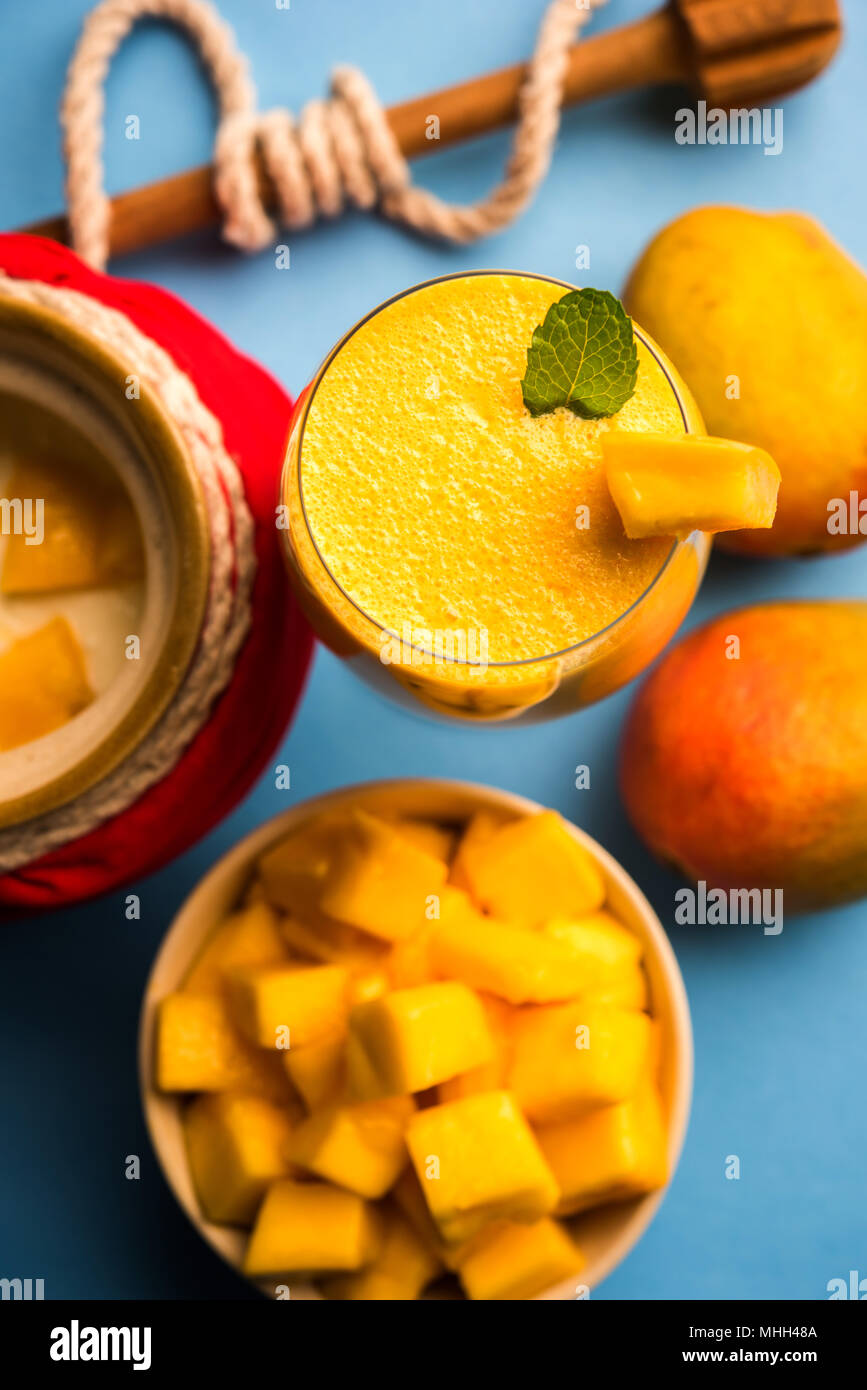 Mango Lassi or smoothie in big glass or small bottles with curd, cut ...